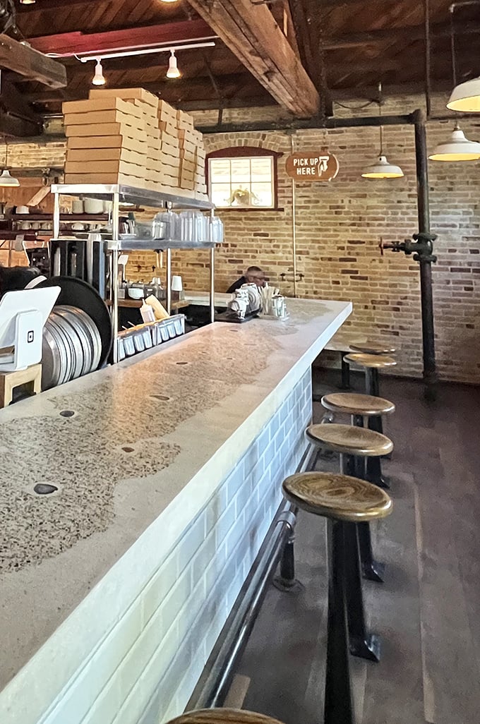 Industrial-chic meets cozy comfort in this thoughtfully designed space where wooden beams and exposed brick create the perfect pizza-eating atmosphere.