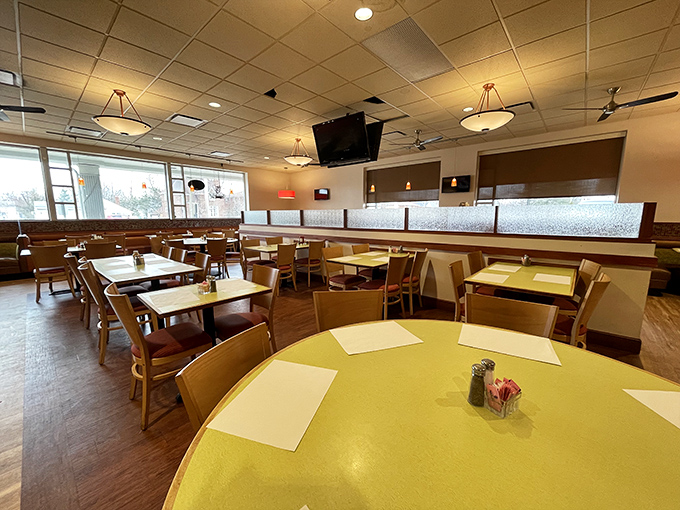 The dining room's warm wood tones and yellow tables create that perfect "everybody knows your order" vibe where comfort food meets comfortable seating.