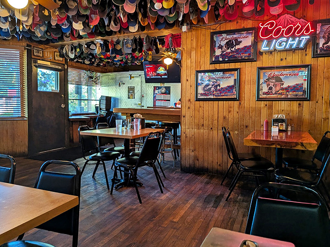 Baseball caps hang like colorful stalactites from the ceiling, each one telling a story of satisfied diners who've made the pilgrimage to burger paradise.