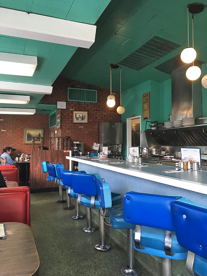 Step into this mint-green time capsule where blue vinyl stools and brick walls create diner perfection.