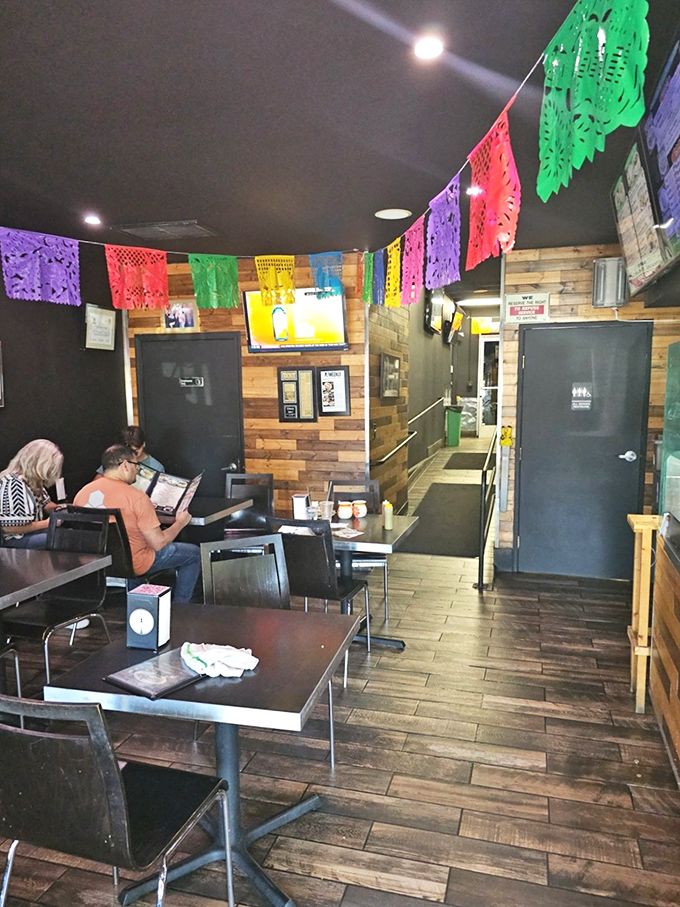 Colorful papel picado banners dance overhead in the cozy dining room, creating a festive atmosphere that matches the vibrant food.