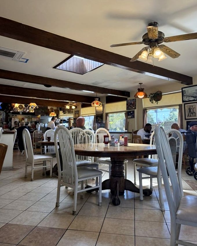 Wooden beams, ceiling fans, and white chairs create that perfect "time stood still" atmosphere where conversations flow as freely as the coffee refills.