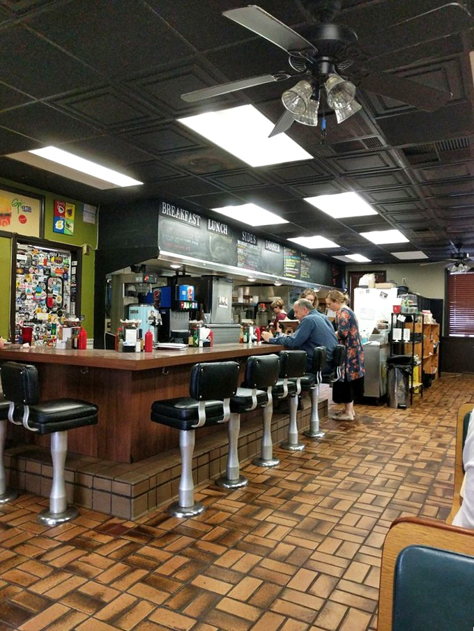 Classic diner counter seating where strangers become friends over coffee. The brick floor has heard more food epiphanies than a cooking show marathon.