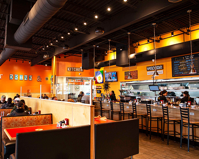 Orange walls that pop like a sunrise, exposed ductwork, and an open kitchen where breakfast dreams become reality.