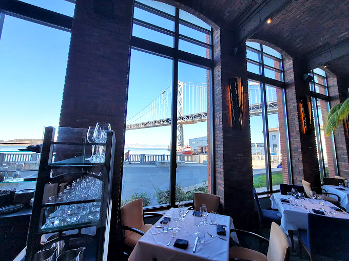 Table with a view? More like view with a table. The floor-to-ceiling windows frame the Bay Bridge like it's posing for your dinner entertainment.