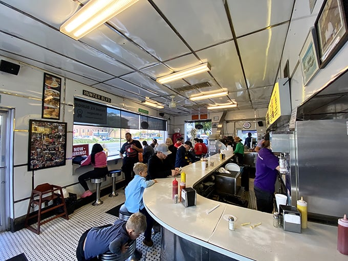 Inside this slider sanctuary, the curved counter brings strangers together in a shared mission: devouring perfect little burgers while watching the griddle ballet unfold.
