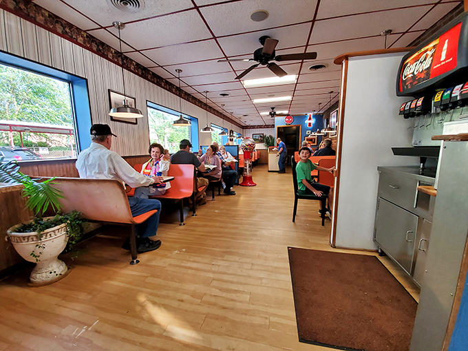 Inside Hot Dog World, wood paneling and orange booths create that perfect time-capsule vibe where conversations flow as freely as the fountain drinks.