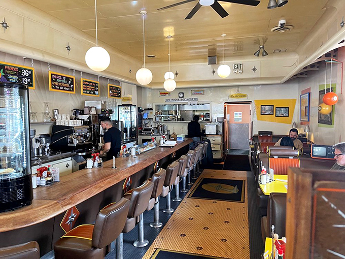 The classic diner counter invites solo diners to perch and watch culinary magic unfold while globe lights cast their warm, nostalgic glow.