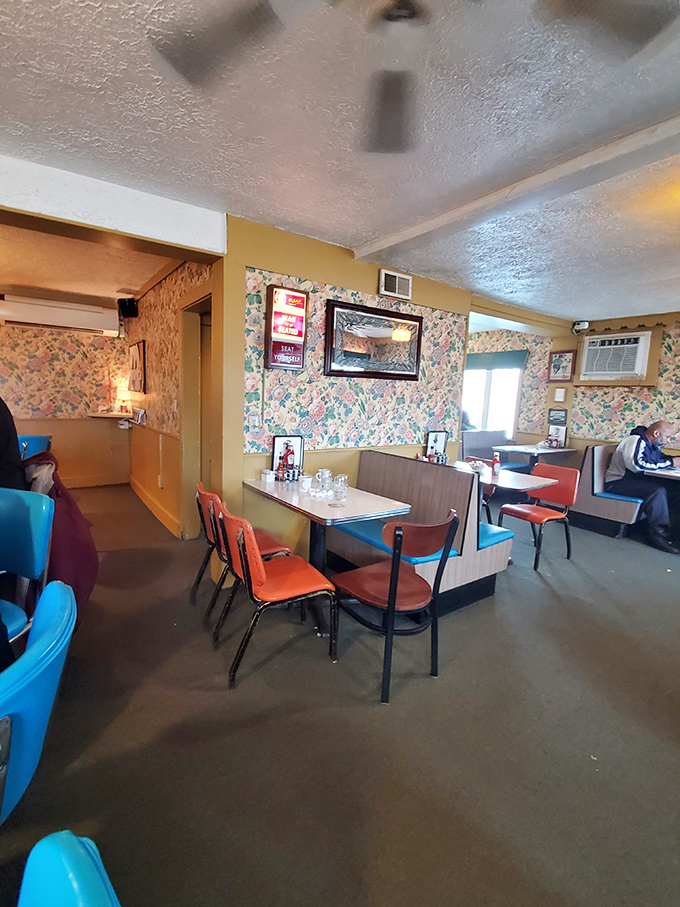Classic diner aesthetics in full bloom &ndash; floral wallpaper, vinyl booths, and those unmistakable orange chairs that somehow feel like coming home.