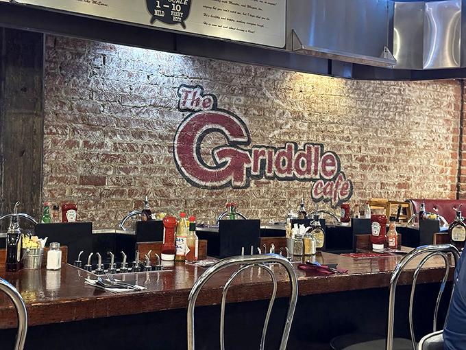 The exposed brick wall proudly displays The Griddle Cafe's logo, while counter seating offers breakfast voyeurs a front-row view of the pancake artistry in action.