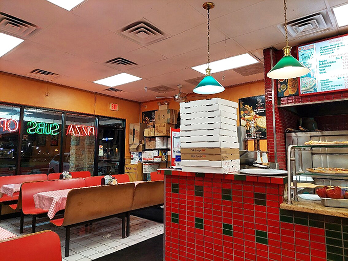 Classic red and green tiled counter, stacked pizza boxes, and those iconic pendant lights—this is pizza joint perfection in its purest form.