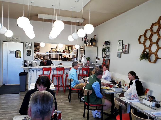 Inside, globe pendant lights cast a warm glow over the cozy space, where breakfast dreams come true amid honeycomb wall art.