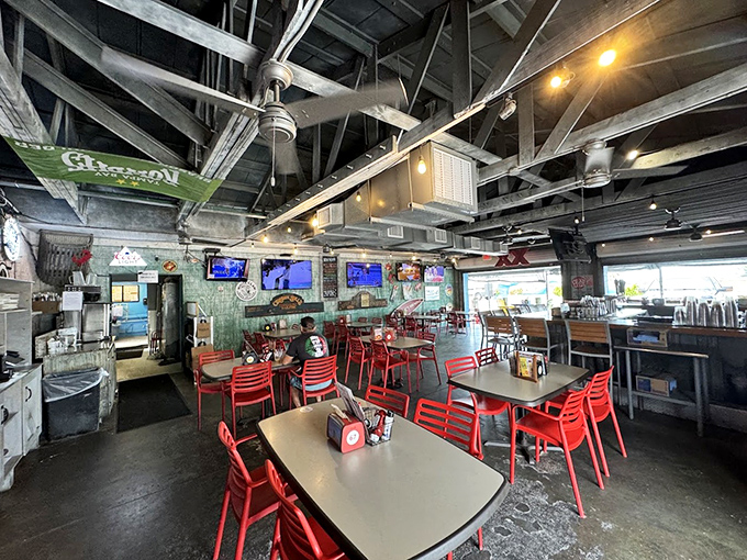 Industrial-chic meets coastal charm with those punchy red chairs. The exposed ceiling beams aren't trying to impress anyone, which somehow makes them all the more impressive.