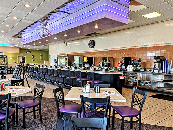 Inside, the counter stretches like a runway for comfort food, where purple-cushioned stools invite solo diners to watch the short-order ballet unfold.