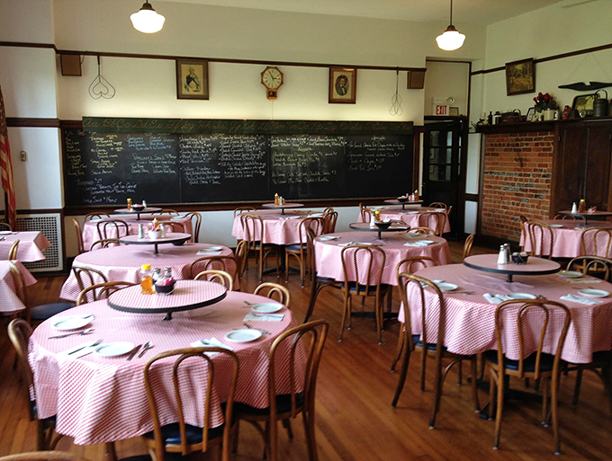 Red and white checkered tablecloths beneath vintage schoolroom lights create the perfect setting for lessons in comfort food excellence.