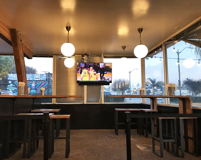 Inside, globe pendant lights cast a warm glow over wooden communal tables, creating that rare space where comfort meets cool without trying too hard.