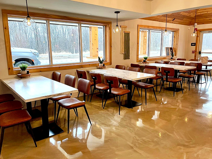 Sunlight floods through large windows, illuminating a dining space where modern meets rustic in perfect harmony.