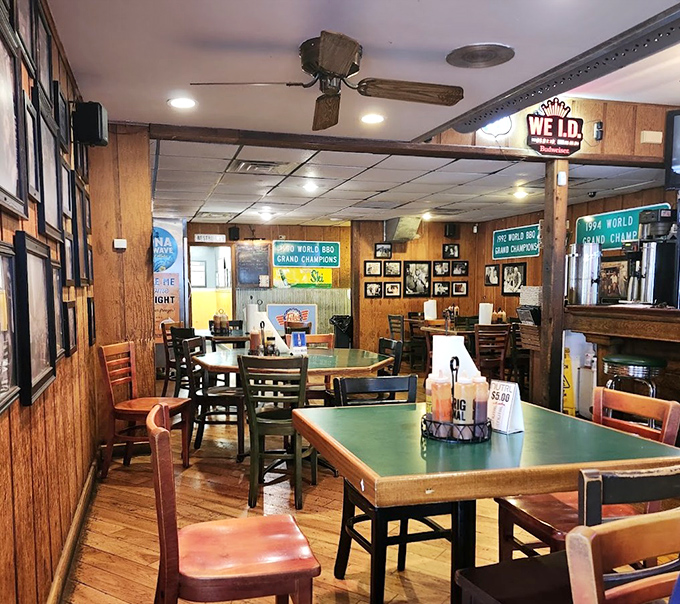 Wood-paneled walls covered in competition banners tell you everything: this isn't just dinner, it's a barbecue hall of fame with tables.