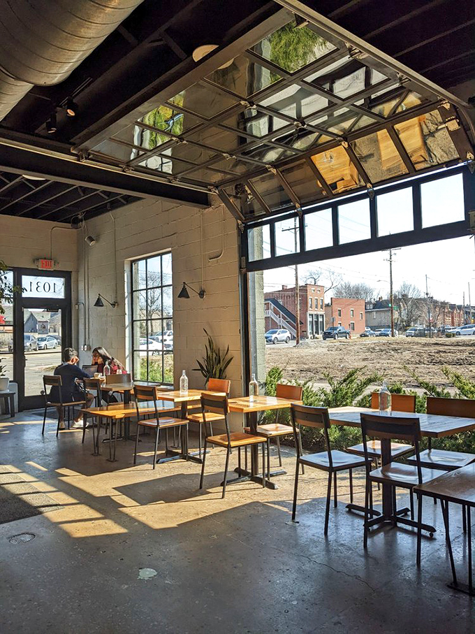 Industrial chic meets cozy comfort as sunlight streams through garage-door windows, turning ordinary coffee moments into something magical.