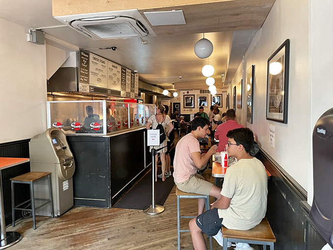Inside, the narrow space buzzes with anticipation as hungry patrons line up for their turn at cheesesteak nirvana.