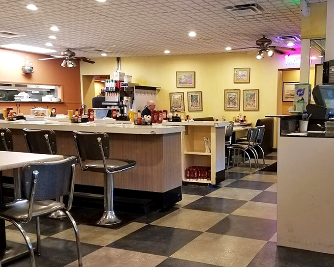 Classic diner DNA on full display: checkered floors, counter seating, and yellow walls that have witnessed decades of breakfast conversations.