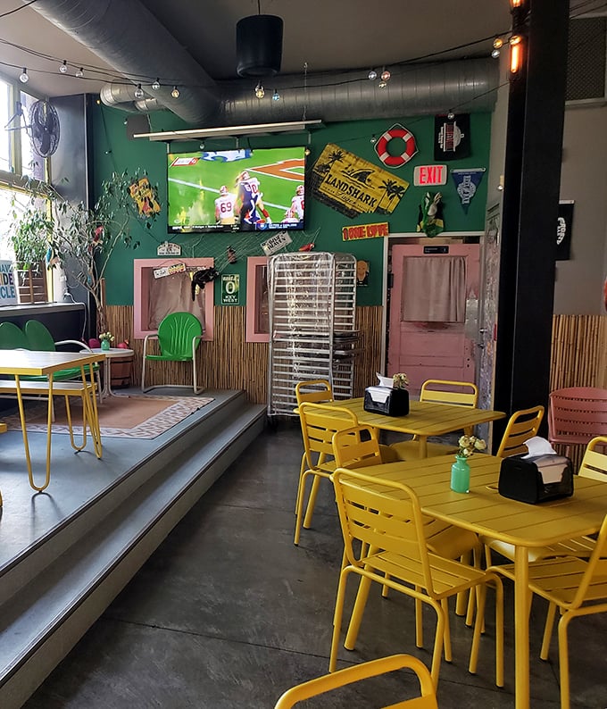 Yellow chairs pop against green walls in this playful space where industrial meets whimsy. The TV ensures you won't miss the game while indulging.