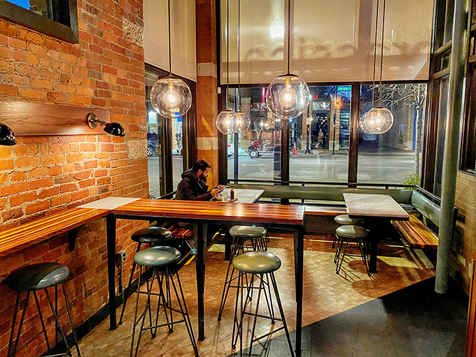 Exposed brick walls and globe pendant lights create that rare atmosphere where hipsters and grandparents feel equally at home. Cozy industrial chic done right.