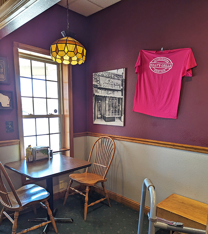 The cozy interior features warm purple walls, vintage-style pendant lighting, and wooden chairs that have supported countless happy diners experiencing butter burger bliss