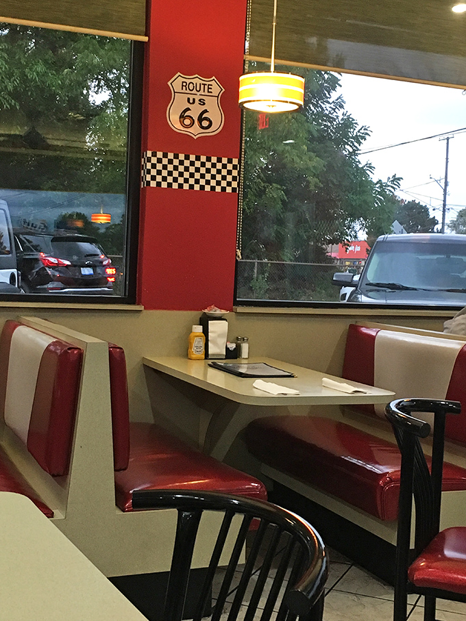 Classic Americana at its finest – red vinyl booths, Route 66 memorabilia, and that unmistakable diner ambiance. The checkered racing motif reminds you this is pure Michigan motor culture.