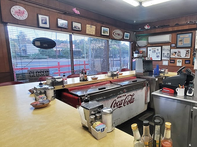 Behind the counter, a vintage Coca-Cola cooler whispers stories of breakfasts past while wood-paneled walls display decades of Los Angeles history.