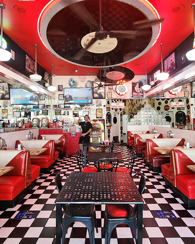 Red vinyl booths, checkered floors, and vinyl records suspended from the ceiling—this isn't decoration, it's a full-sensory portal to simpler times.