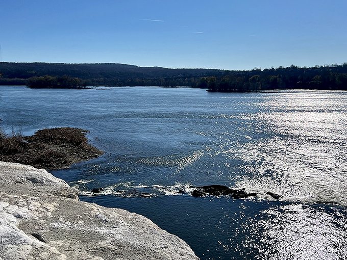 The river sparkles like scattered diamonds, creating a mirror that doubles the beauty of this limestone wonderland.