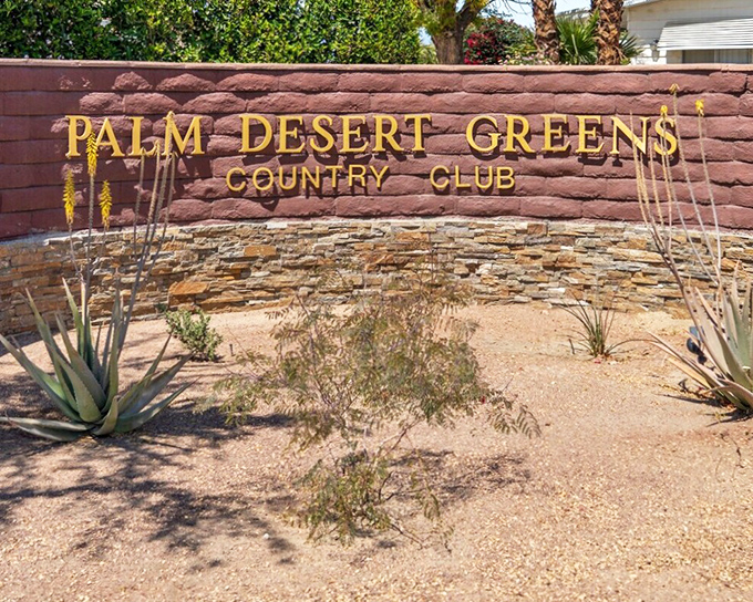 Desert-appropriate landscaping frames the entrance sign, nature's way of saying "welcome home" without the water bill.