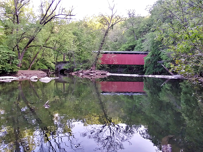 Mirror, mirror on the creek: The bridge's reflection creates a perfect symmetry in the still waters, doubling the magic for anyone lucky enough to discover this spot.