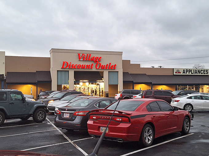 Village Discount Outlet's bold red signage promises an adventure where yesterday's castoffs become tomorrow's conversation pieces.