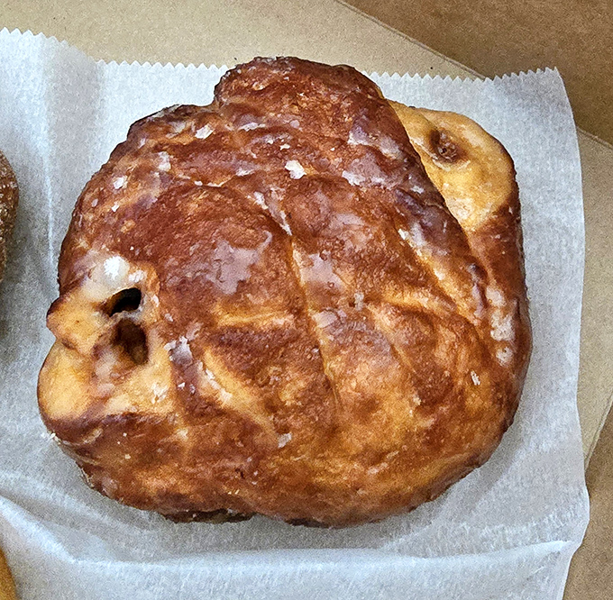 The legendary apple fritter in all its glazed glory. This isn't just fried dough &ndash; it's an architectural marvel of crispy edges, tender interior, and apple-cinnamon pockets that would make Frank Lloyd Wright jealous.
