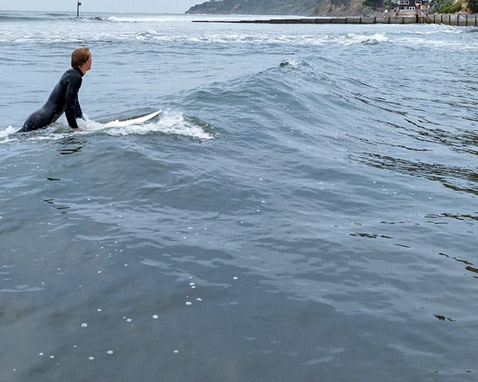 A surfer reads the morning's watery newspaper, contemplating which wave will make the perfect ride. Bolinas surf culture in its natural habitat.