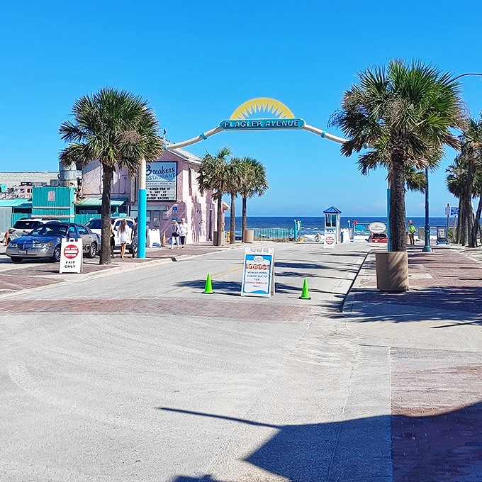The iconic Flagler Avenue arch stands as a sunny yellow gateway to paradise. Palm trees stand guard at this beloved entrance to New Smyrna's beach access.