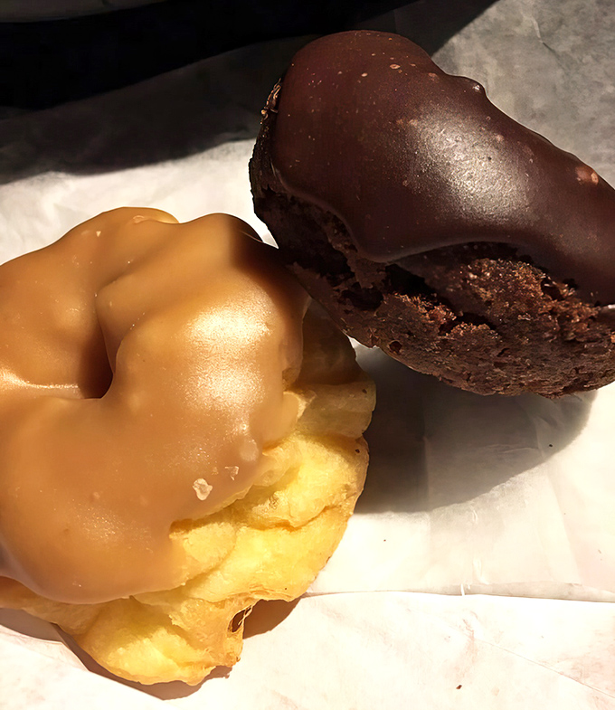 The dynamic duo of donut perfection. That golden French cruller with its delicate glaze sits proudly next to its chocolate counterpart like dessert royalty.
