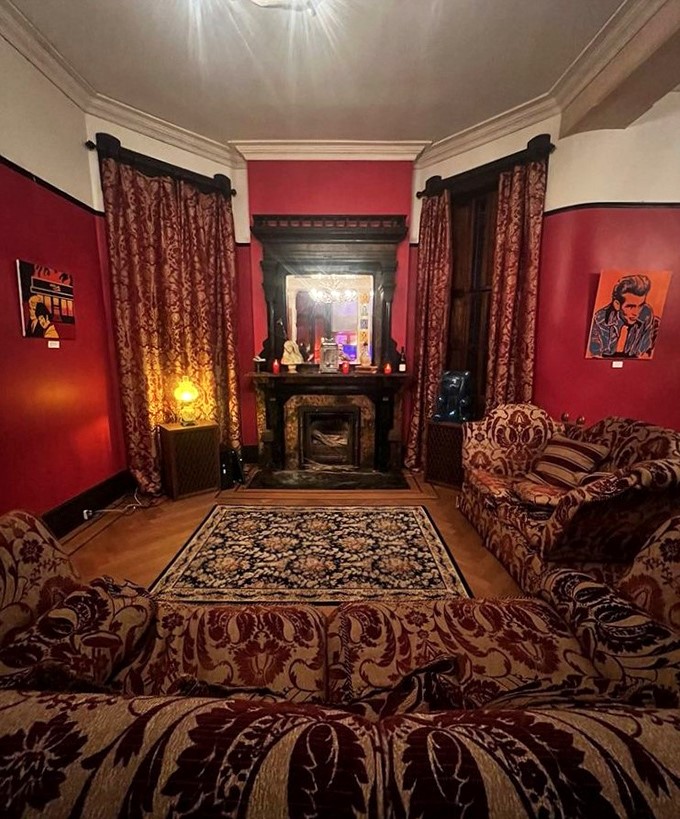 Rich crimson walls embrace vintage furnishings in this parlor where you half-expect to hear phantom piano notes drifting through the air.