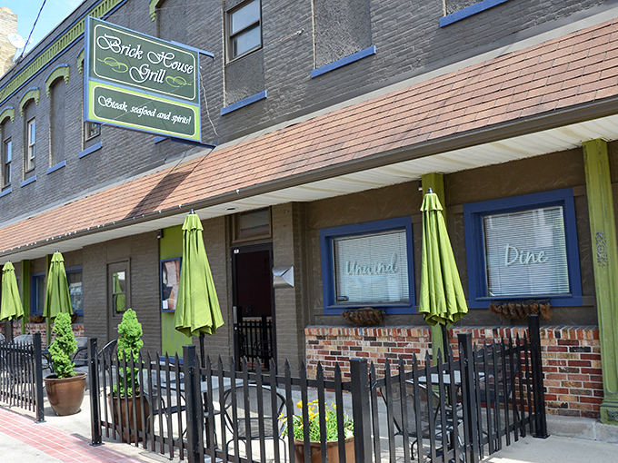 Brick House Grill's inviting patio beckons with lime-green umbrellas, promising seafood and spirits in a setting where conversations flow as freely as the drinks.