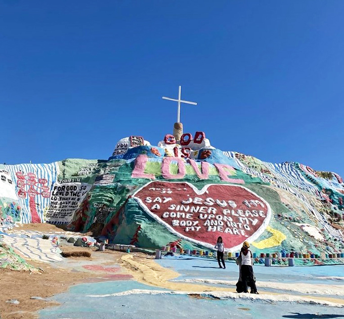 The massive red heart proclaims the mountain's central message, standing out against the azure California sky like a Valentine from the desert.