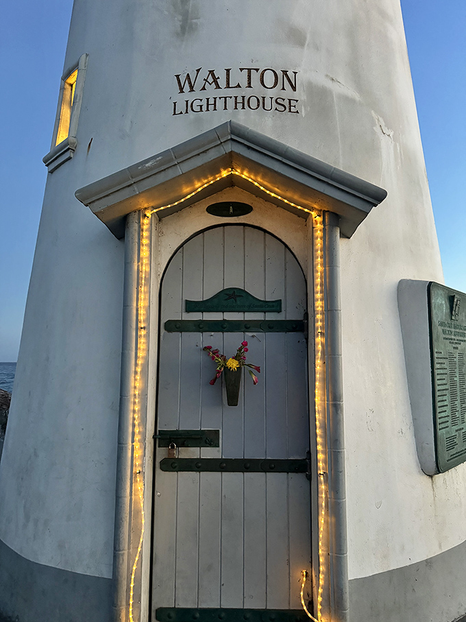 That charming doorway, adorned with twinkling lights and a simple cross, gives this lighthouse the cozy feel of a maritime cottage rather than a navigational aid.