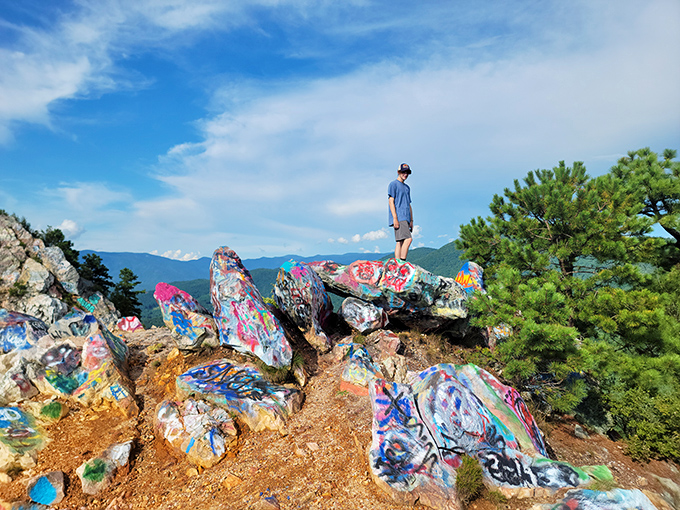 Where street art meets mountain majesty. Bell Mountain's colorful graffiti-covered rocks create a fascinating juxtaposition against the pristine wilderness stretching to the horizon.