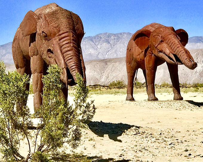 These mammoth metal pachyderms roam the desert landscape eternally, their impressive forms silhouetted against mountains that have witnessed millions of years of evolution.
