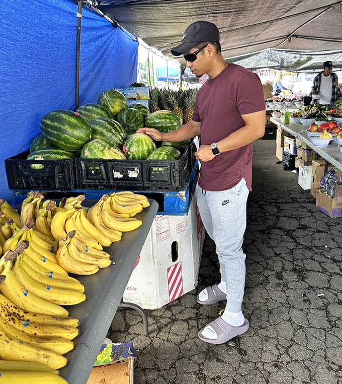 The produce whisperer at work. Nothing beats the simple pleasure of thumping watermelons while pretending you actually know what you're listening for.