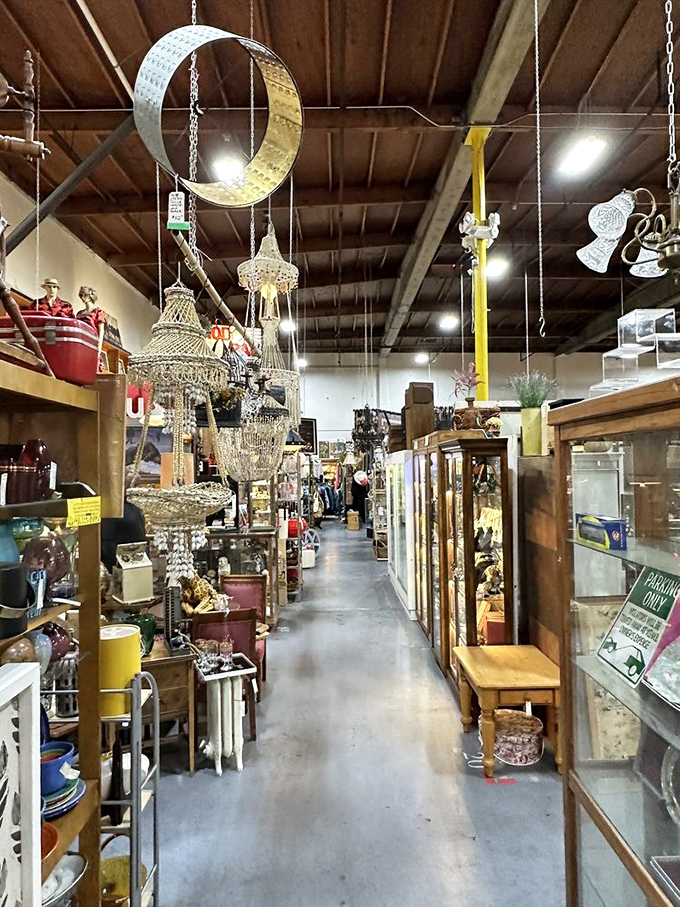 Ornate chandeliers dangle overhead like forgotten ballroom dreams, illuminating pathways to countless vintage treasures below.