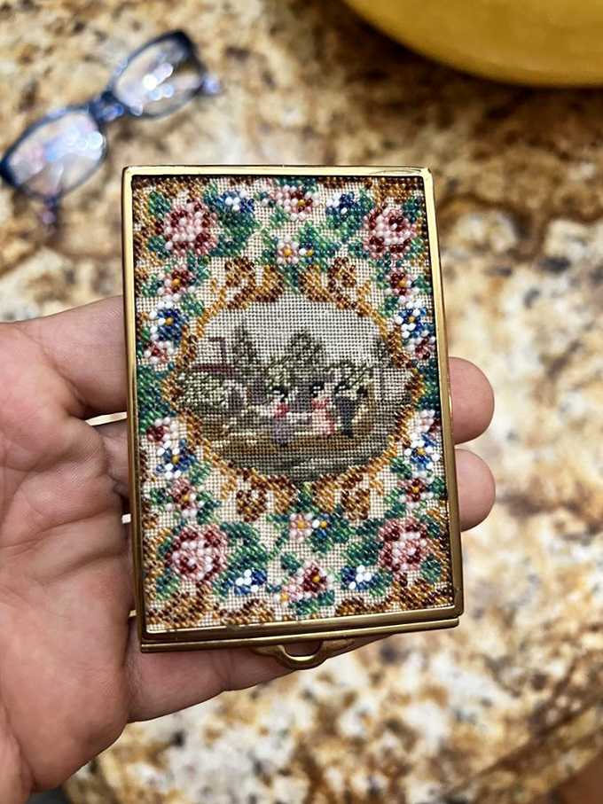 Intricate needlework transforms this vintage powder compact into a miniature masterpiece—proof that beauty endures across generations.