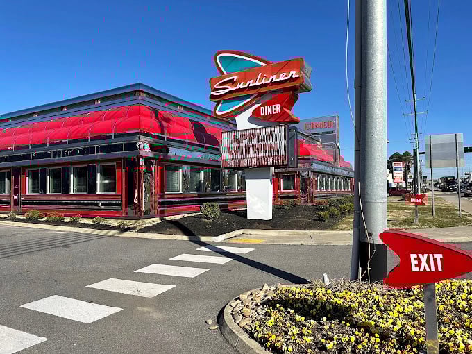 Sunliner Diner's cherry-red exterior gleams in the sunlight, a 1950s time capsule promising milkshakes and memories.