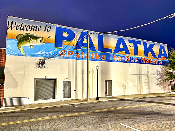 Night lights, big city? Nope—just Palatka after dark, where that fish on the banner looks ready to jump right off into evening adventures.